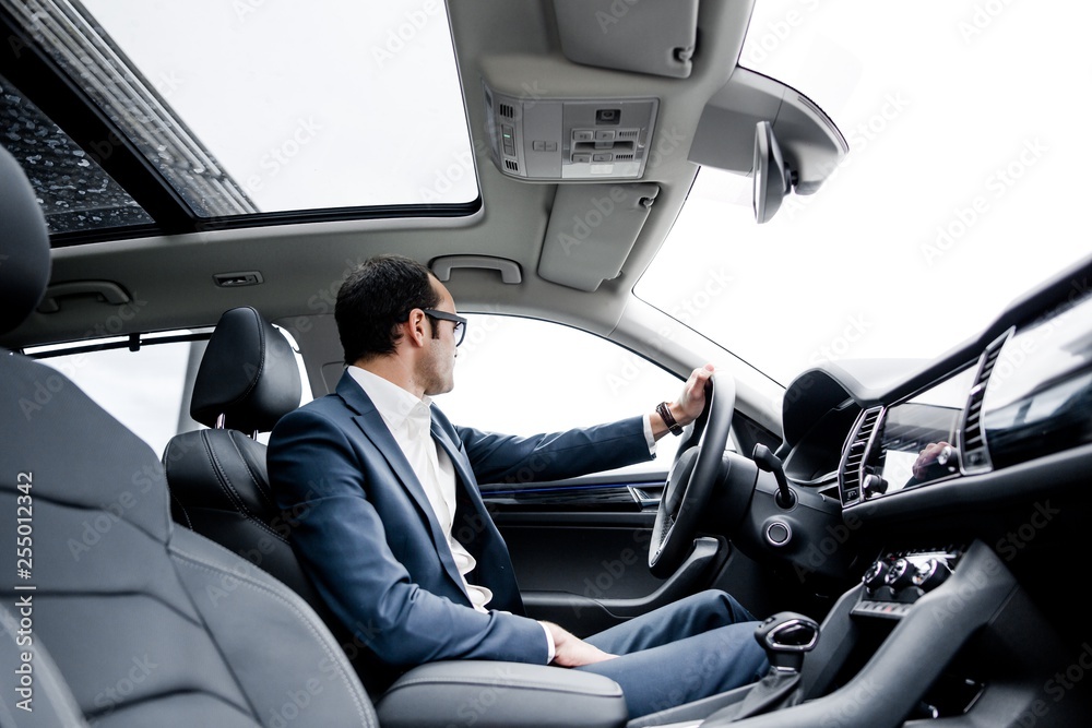 Driver in glasses sitting behind the wheel of a car with a panoramic ...