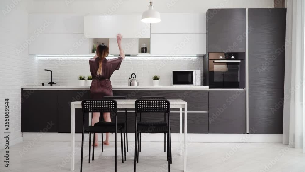 Young attractive girl in satin robe prepares her morning coffee in the ...
