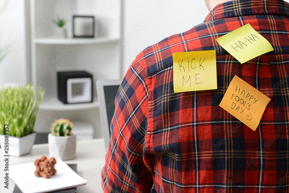 Sticky notes on back of young man working in office. April Fool's Day ...