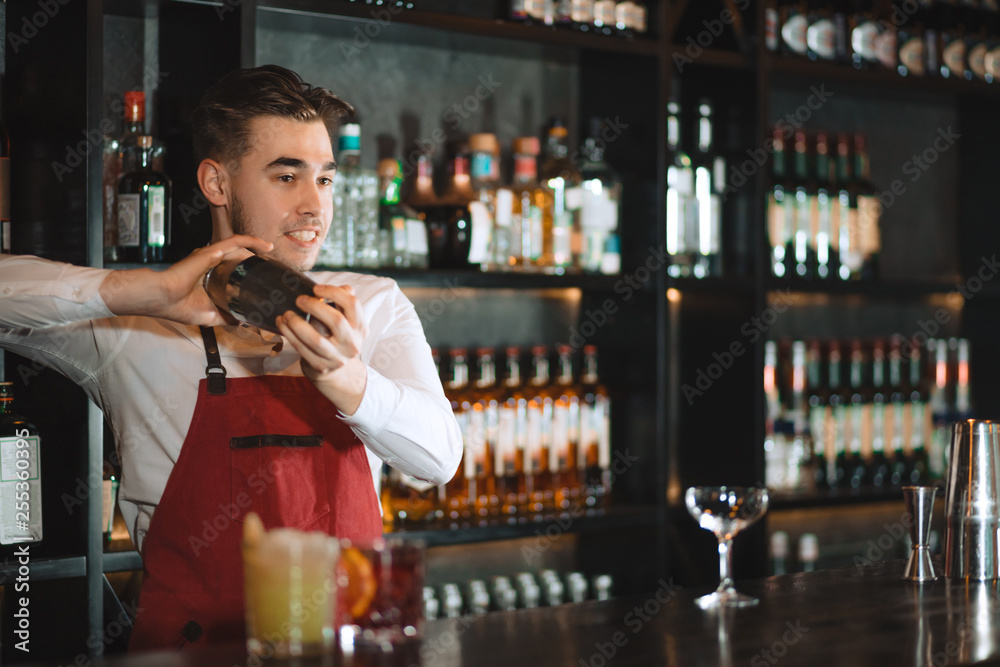 Professional bartender in uniform doing show of his work, holding two ...