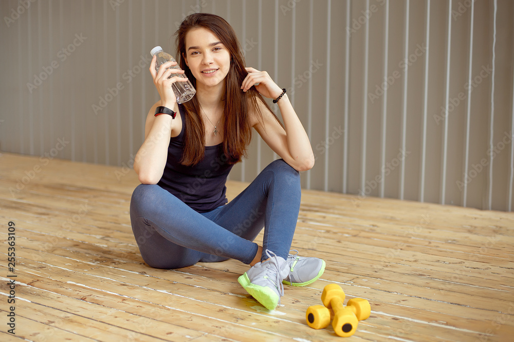 Athletic girl with dark hair in sports uniform holding a bottle of ...