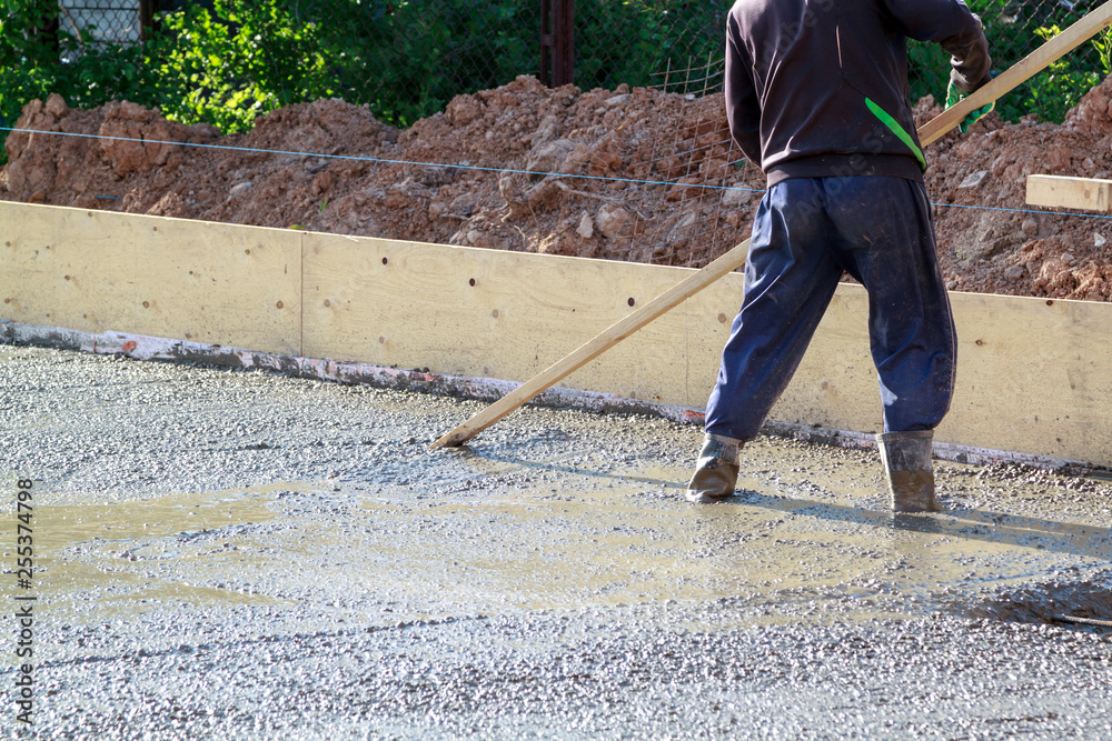 worker in rubber boots stands in uncluttered cement and leveling the ...