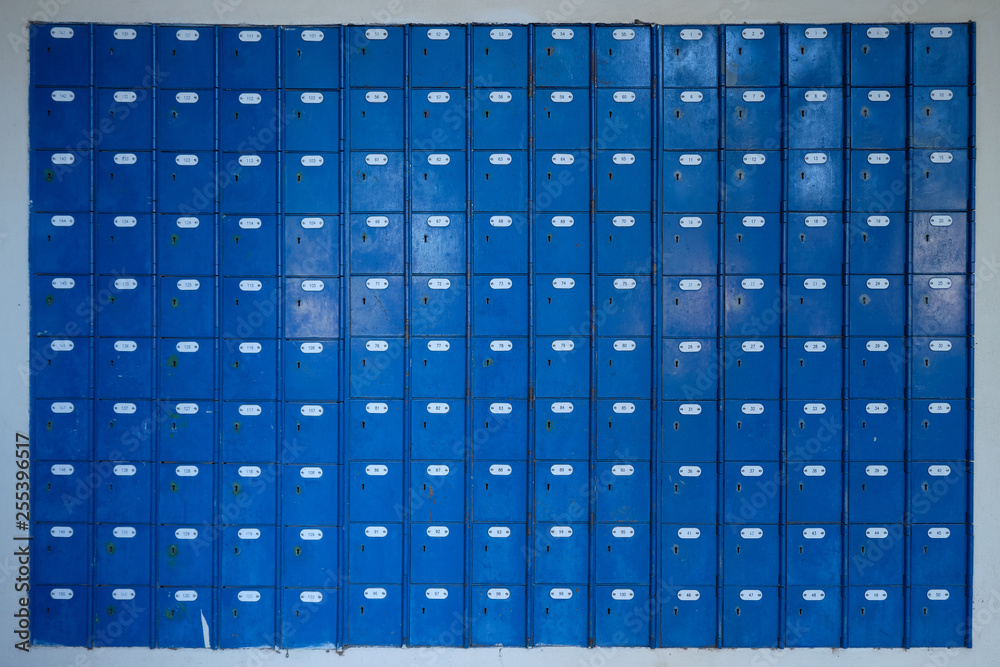 Wall of Antique numbered locked boxes. Box doors are blue with keyhold ...