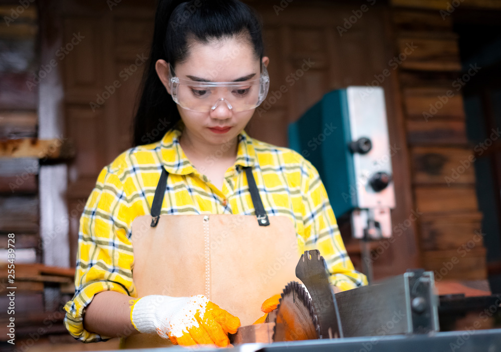 Women standing is craft working cut wood at a work bench with circular ...
