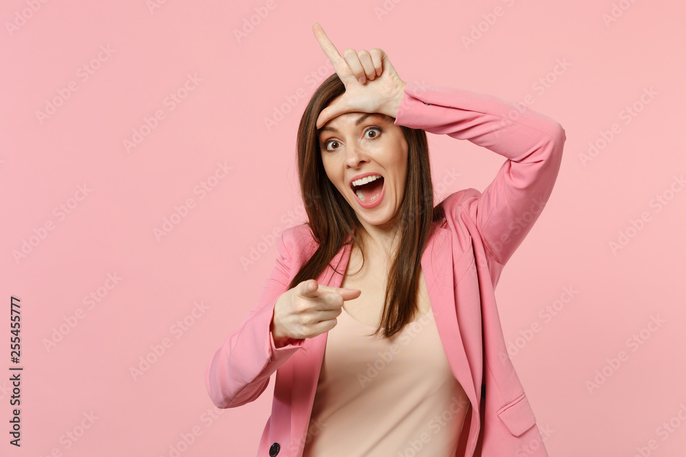 Cheerful young woman in jacket showing loser gesture, pointing index ...