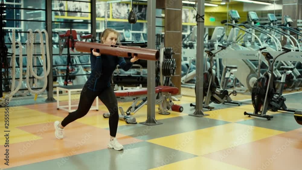 Vidéo Stock Strong athletic woman does squats with a fitness tube in ...