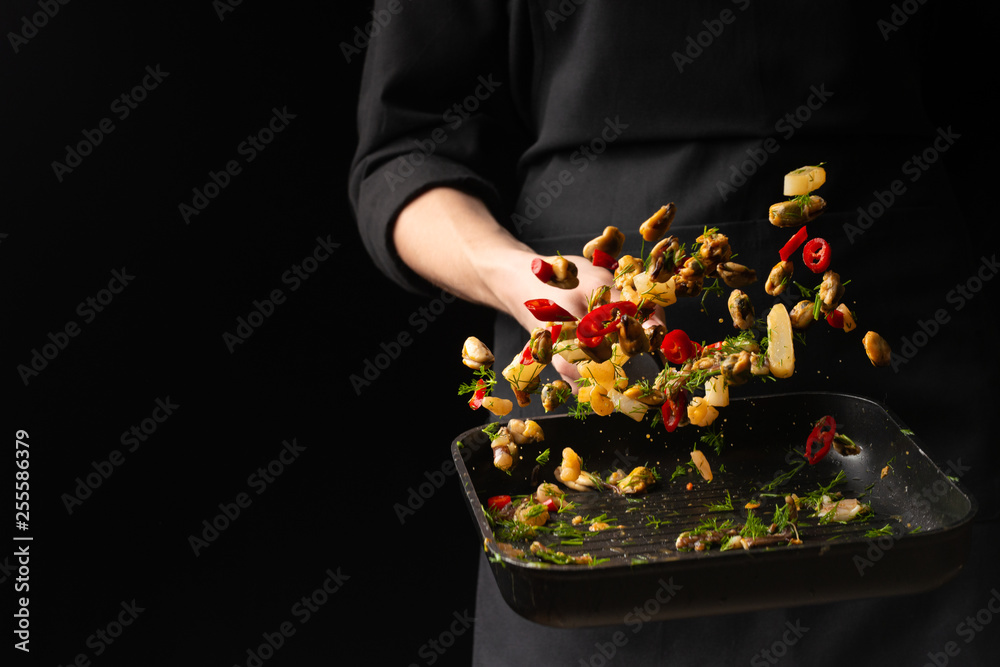Professional chef prepares seafood with spicy chili peppers and greens ...