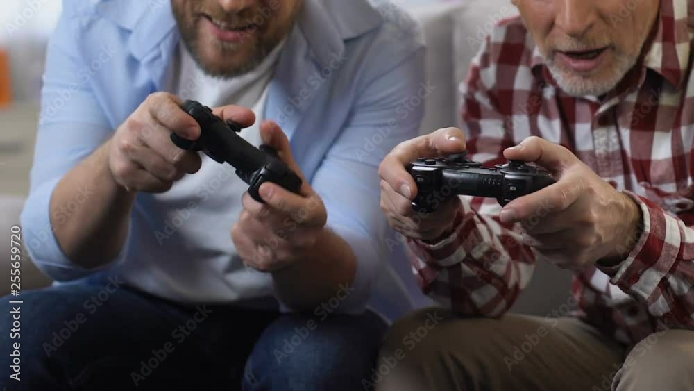 Adult men playing video games using game joysticks, father and son ...