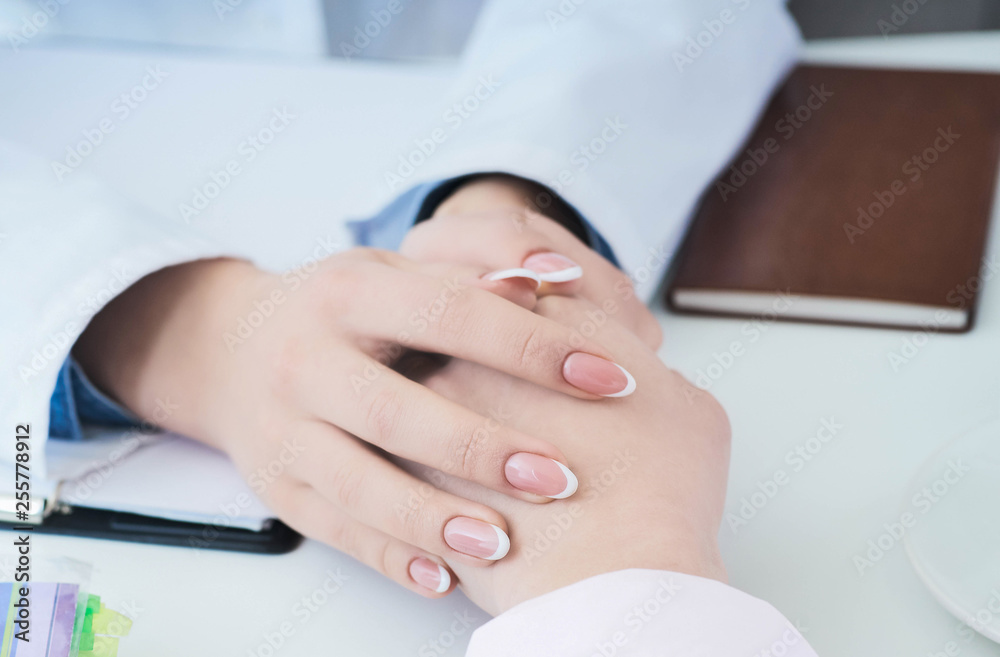 Friendly female doctor hands holding patient hand sitting at the desk ...