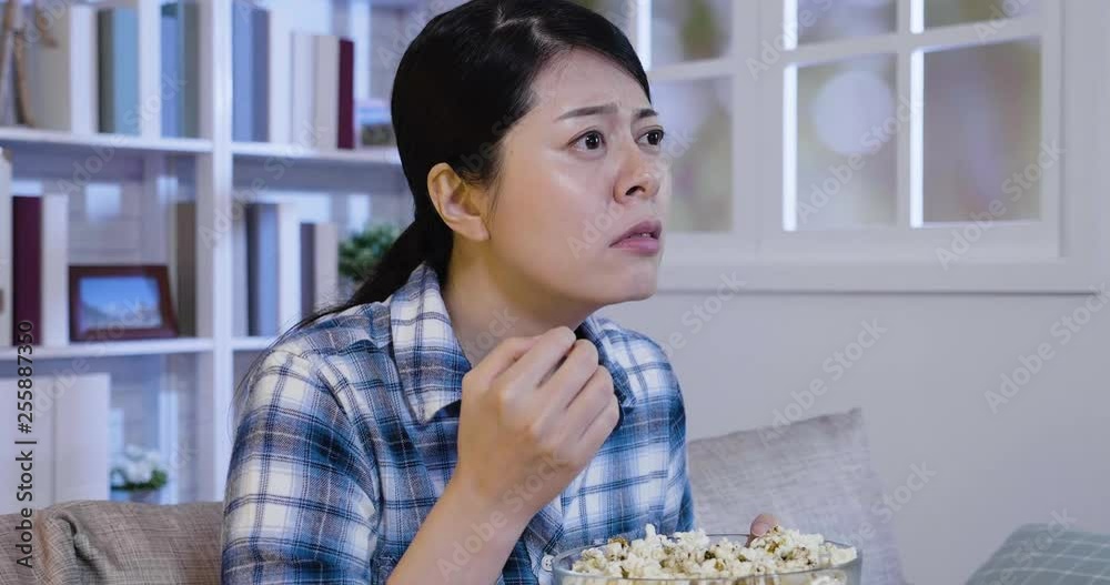 Scared woman watching tv horror movie hiding face behind popcorn bowl ...