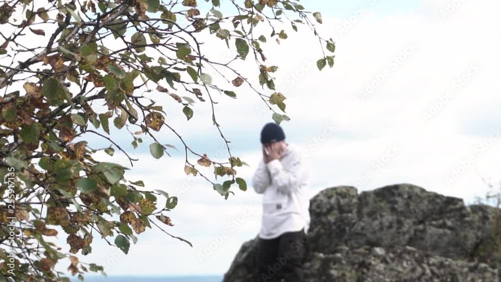Hiker man standing near the boulder, touching his face behind a tree ...