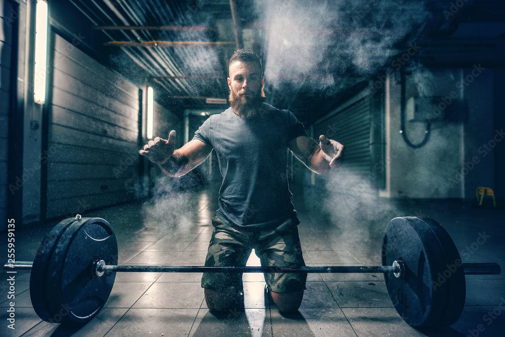 Strong muscular Caucasian bodybuilder clapping hands and crouching in ...
