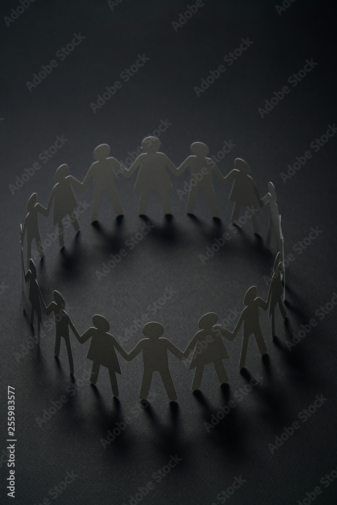 Circle of paper people holding hands on dark surface. Brotherhood ...