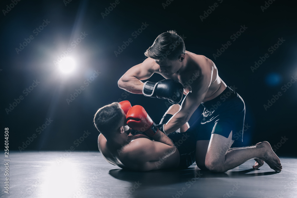 Shirtless strong mma fighter in boxing gloves standing on knees above ...