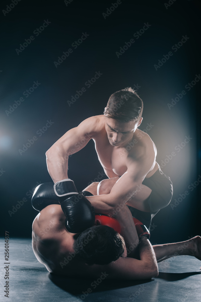 shirtless strong mma fighter in boxing gloves clinching opponent on ...