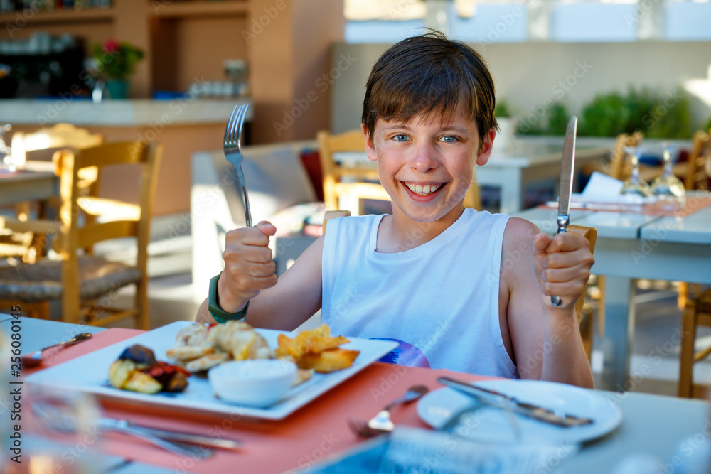 Happy cute boy is starting his dinner. Holding a spoon and fork in the ...