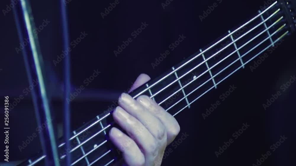 closeup guitarist hand smashes strings on electric guitar neck plays ...