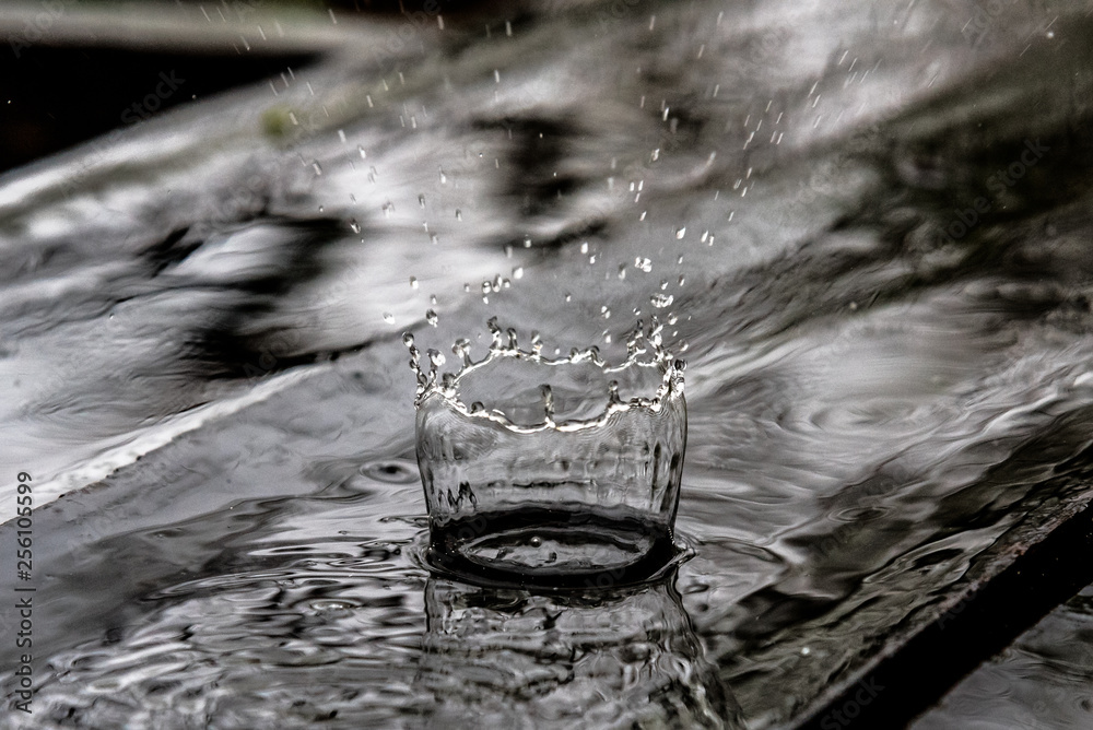 Rain drop splash in wooden floor bouncing and shaping a water crown ...