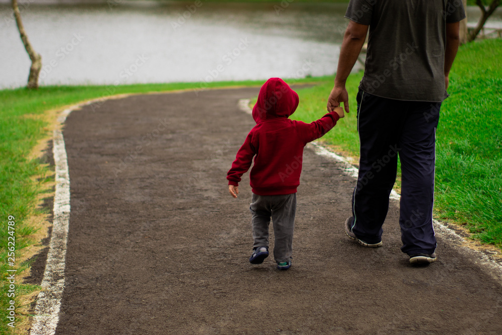 A father walking with his son in a beautiful day with a lake as ...