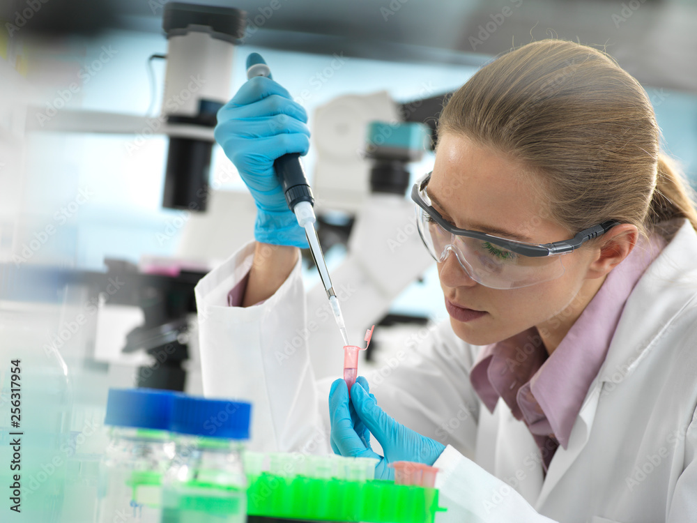 Scientist pipetting sample into a vial ready for automated analysis in ...