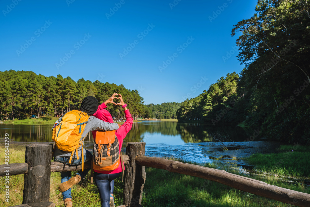 Couples travelers with backpack happy to relax on mountain, with lakes, beautiful ponds pine ...