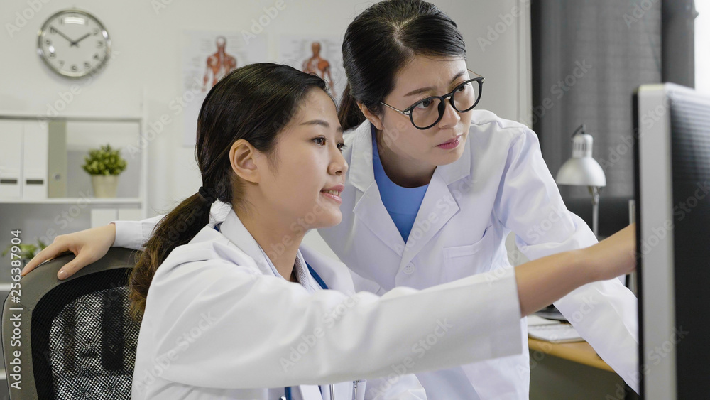 female doctor with stethoscope pointing at screen of computer while ...