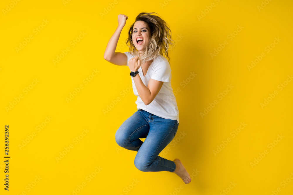 Beautiful young blonde woman jumping happy and celebrating with raised ...