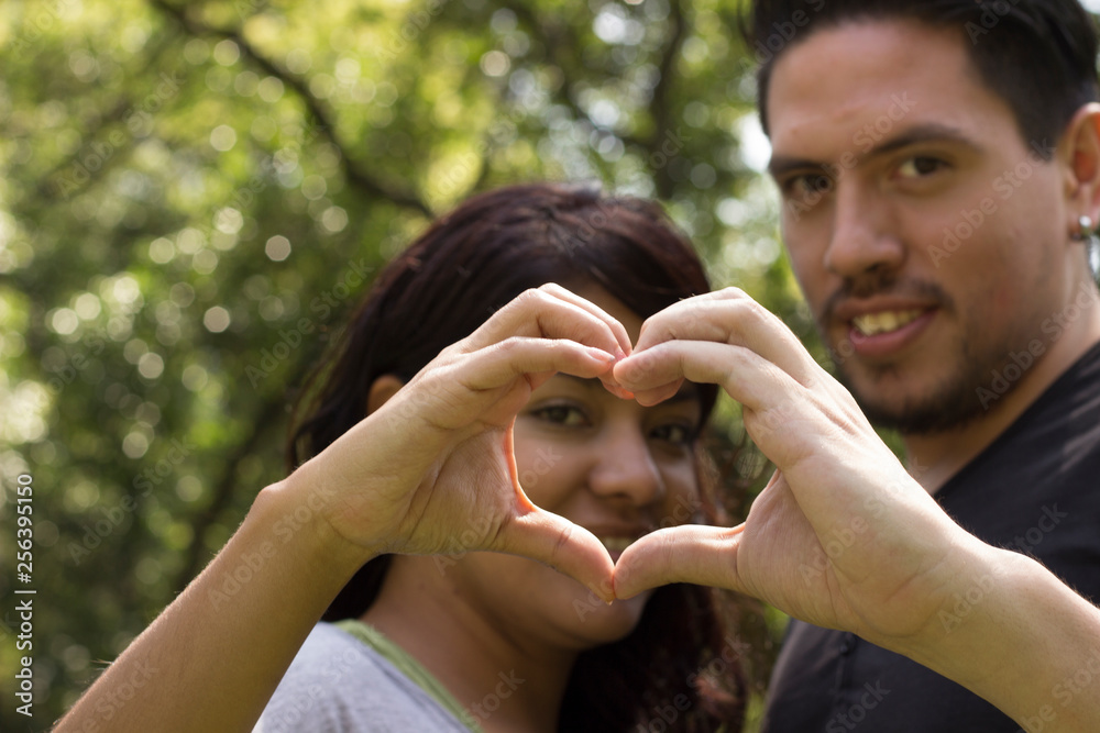 Pareja de jóvenes latinos formando un corazón con sus manos y ...