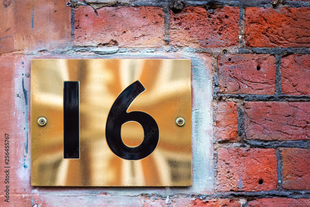 House number 16 witht he sixteen written in black upon a bronze plaque ...