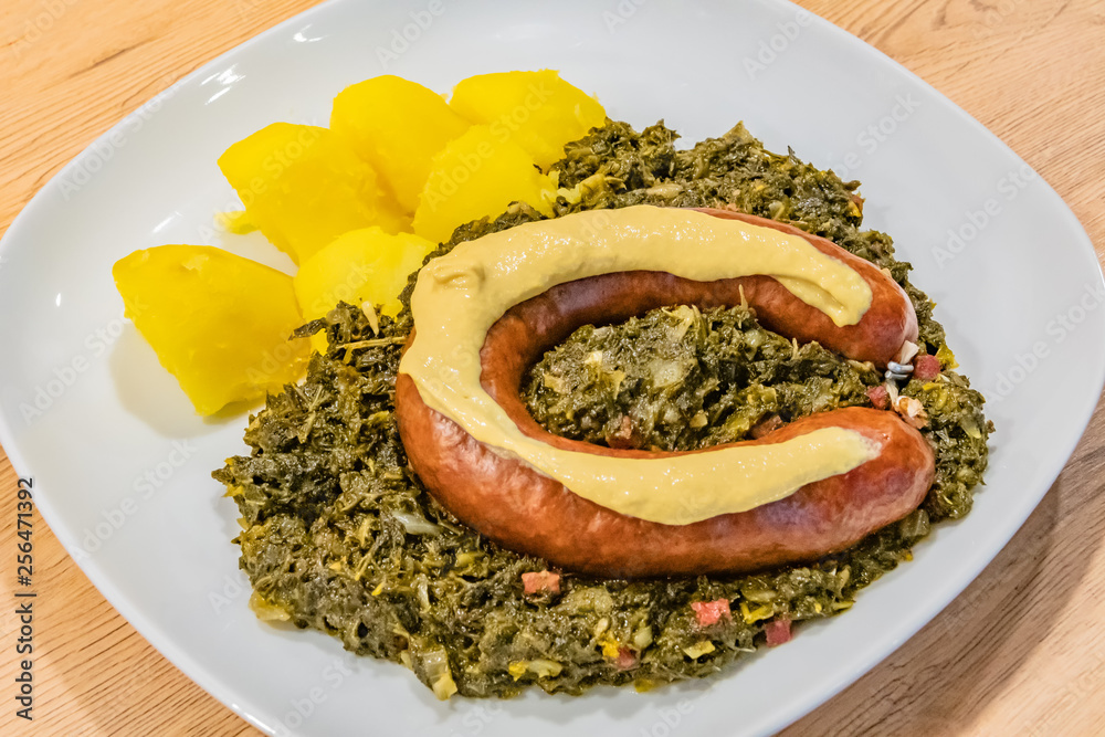 Braunkohl mit Bregenwurst, Senf und Kartoffeln auf weißen Teller Stock ...