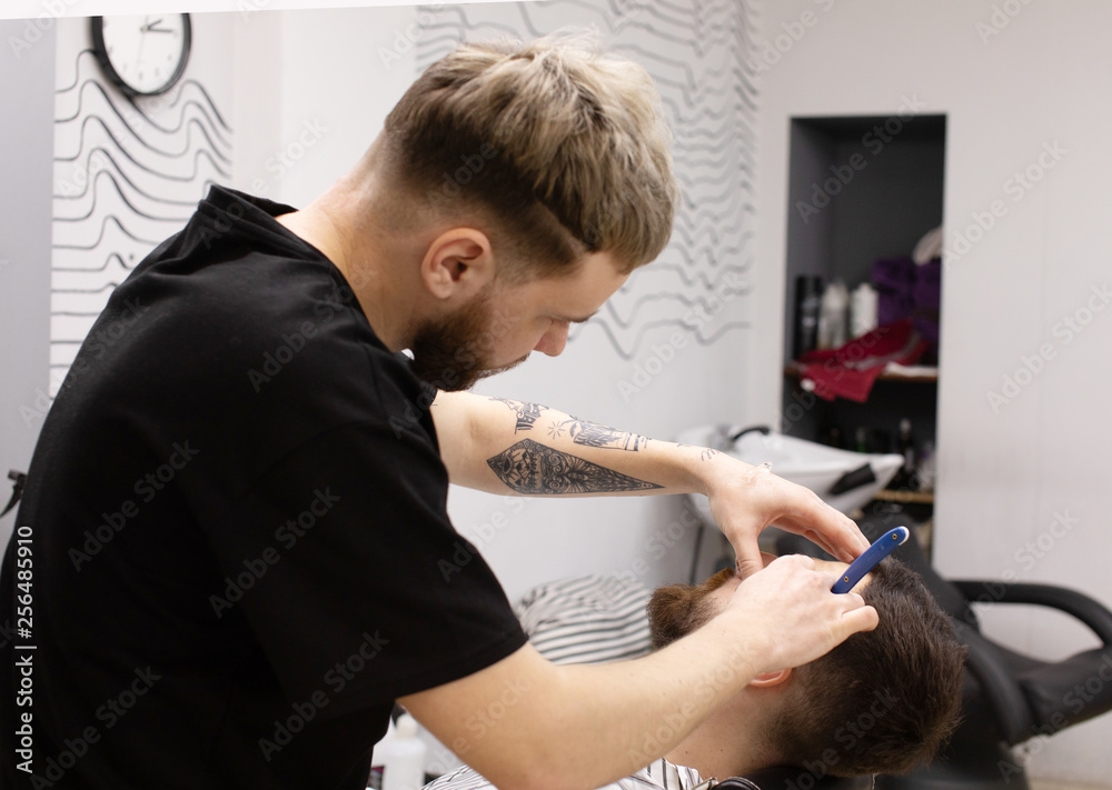 Shaving process of beards in Barbershop. Master makes a haircut beard ...
