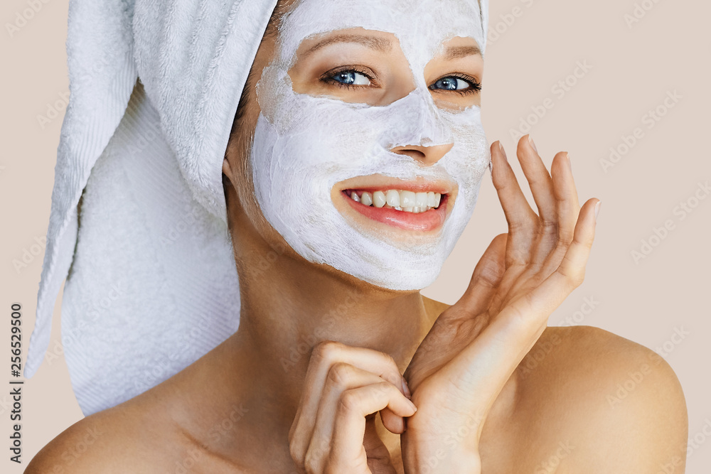 Beautiful young woman applying facial mask on her face. Skin care and ...