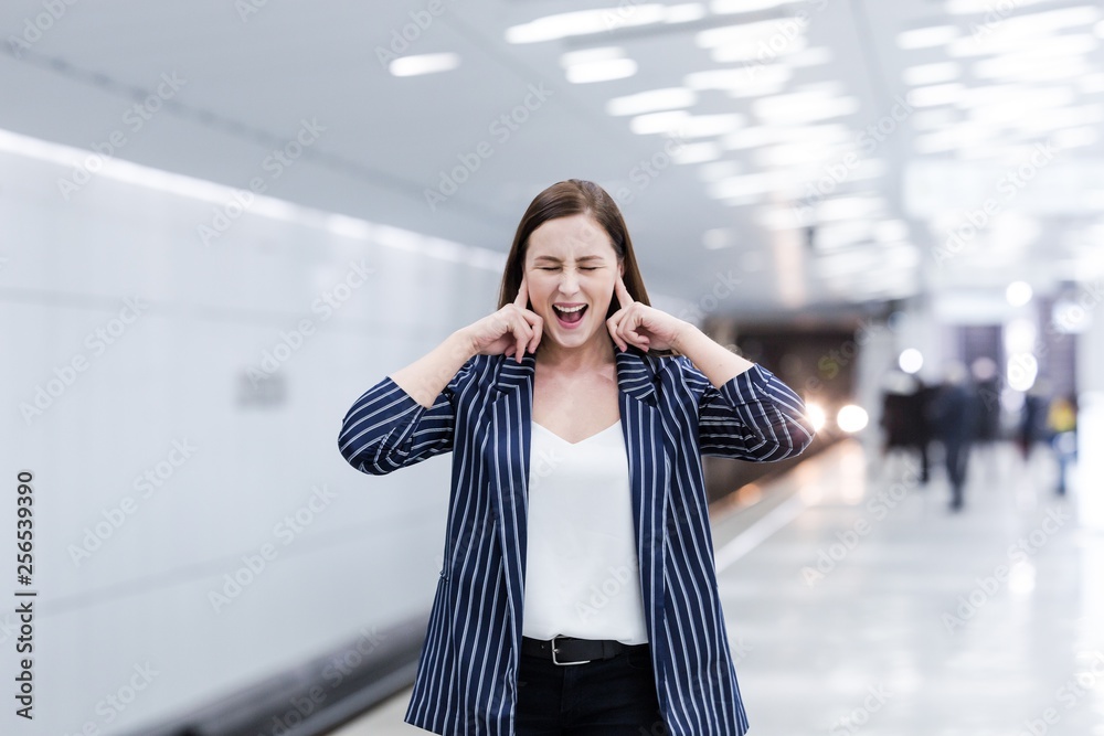 Woman on the subway platform covering her ears screaming from the loud ...