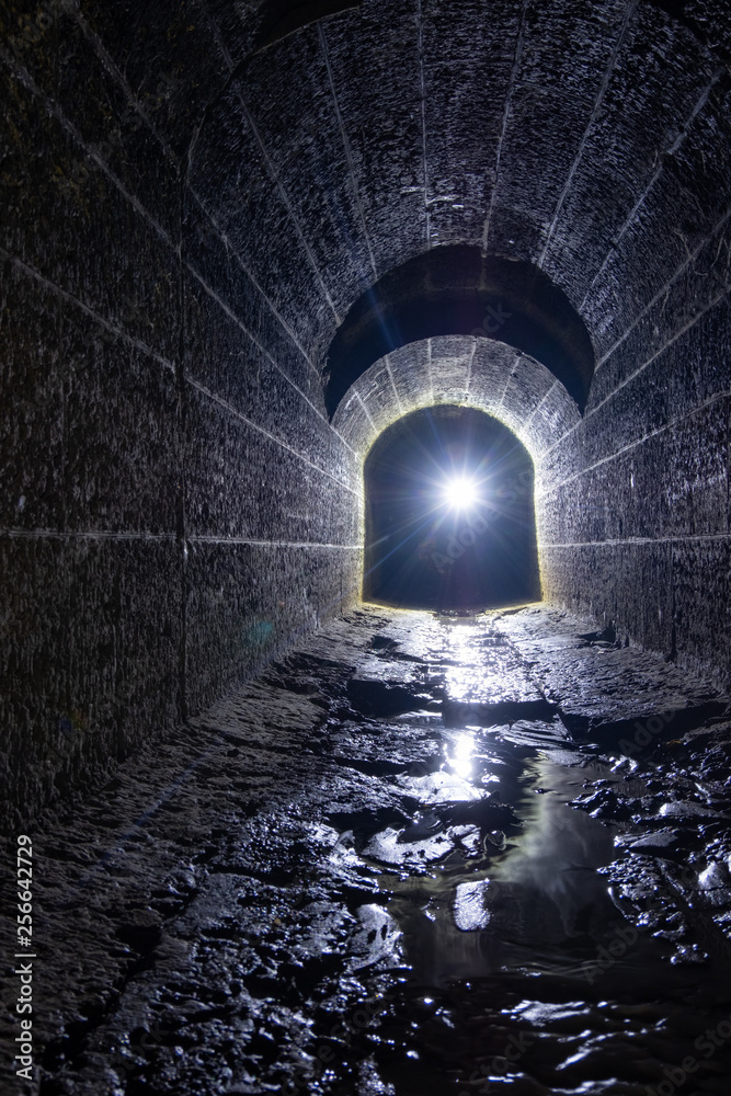 Old vaulted flooded round underground drainage sewer tunnel with dirty ...