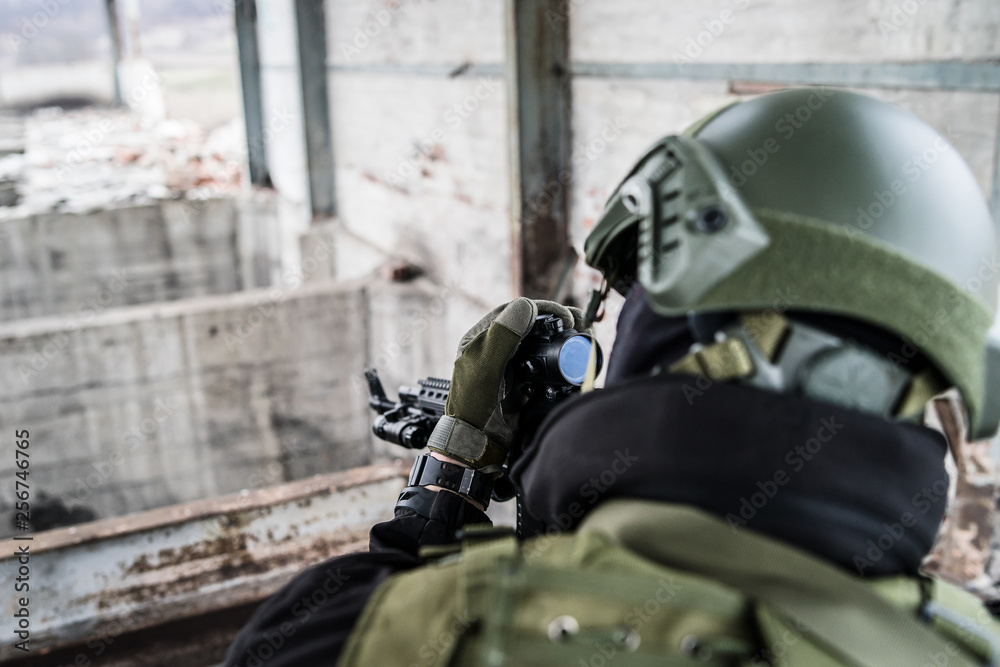 Young Special forces SWAT soldier aiming with assault rifle gun at the ...