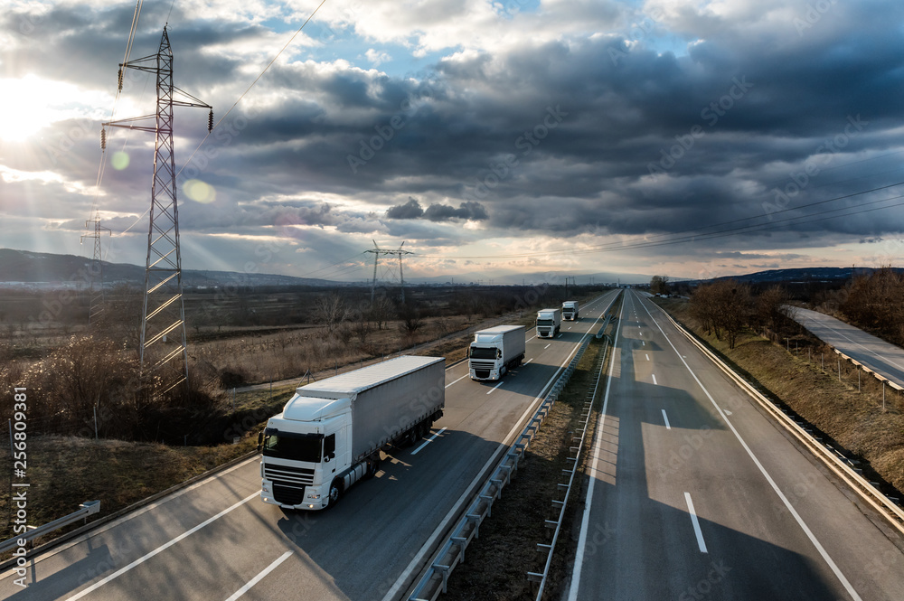 Caravan or convoy of lorry trucks on country highway under a dramatic ...