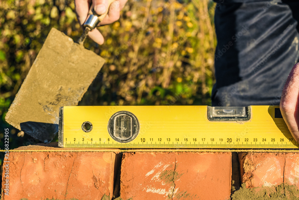 Bricklayer checks the horizontal level of brick masonry wall with a ...