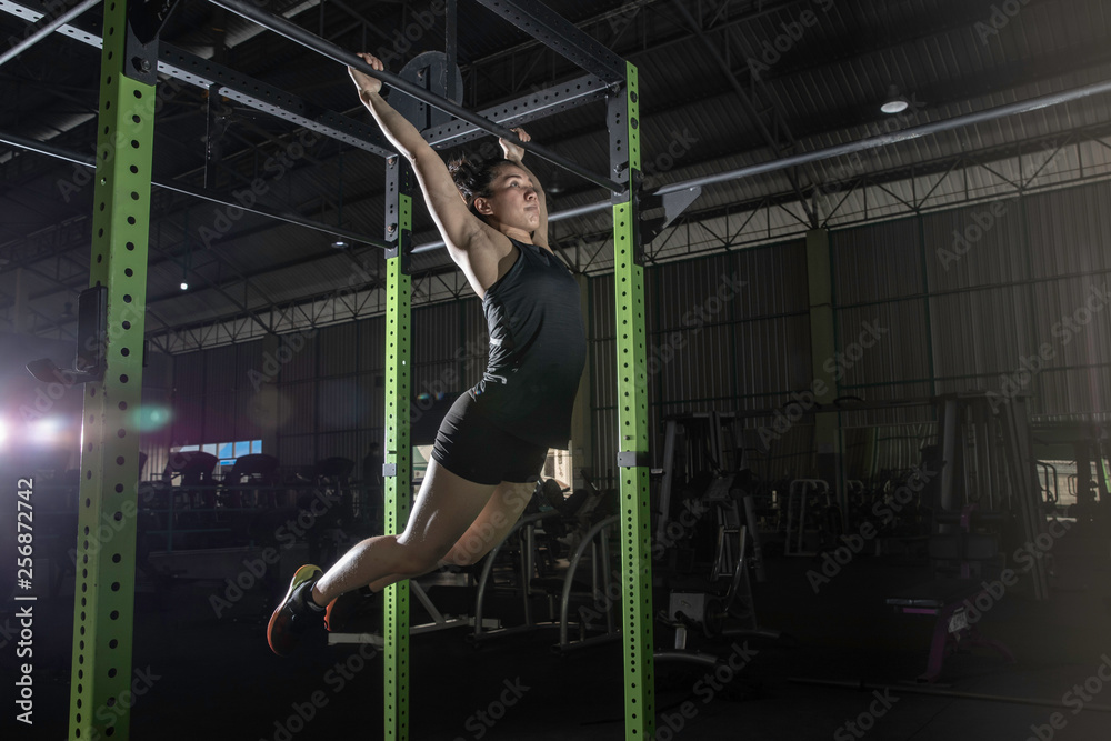 Crossfit athlete woman doing abs exercises on horizontal bar ...