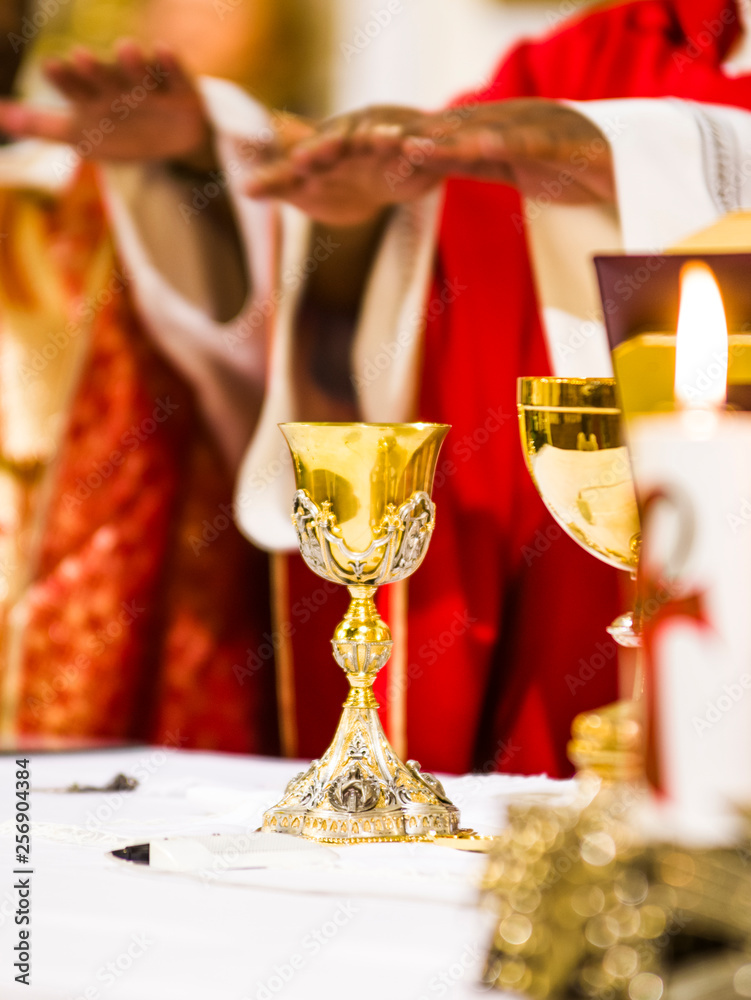 hands of the priest consecrate wine and bread on the altar of holy mass ...