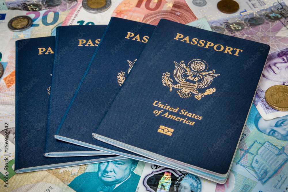 Four USA Passports with a backdrop of foreign currency meant to ...