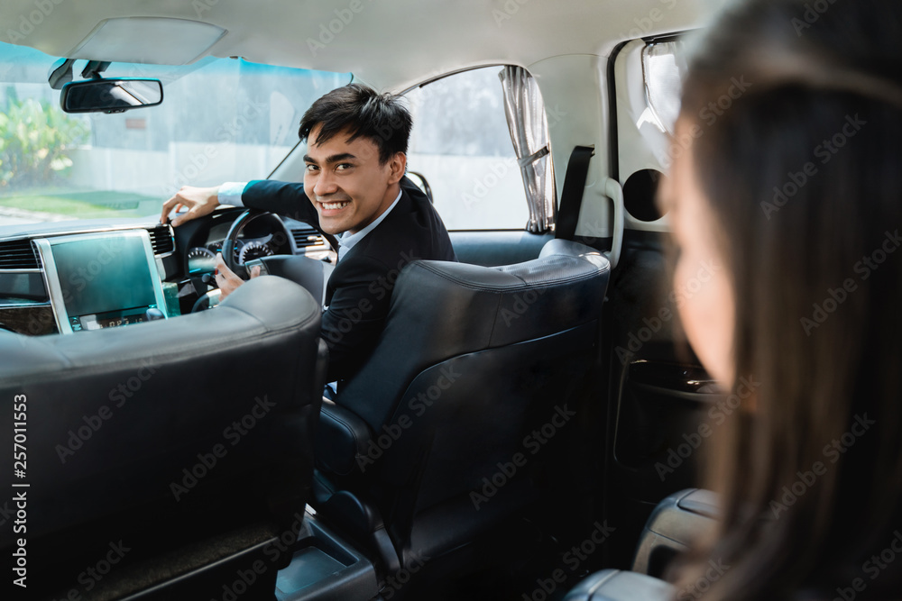 driver in his suit driving luxurious car. looking at his passenger at ...