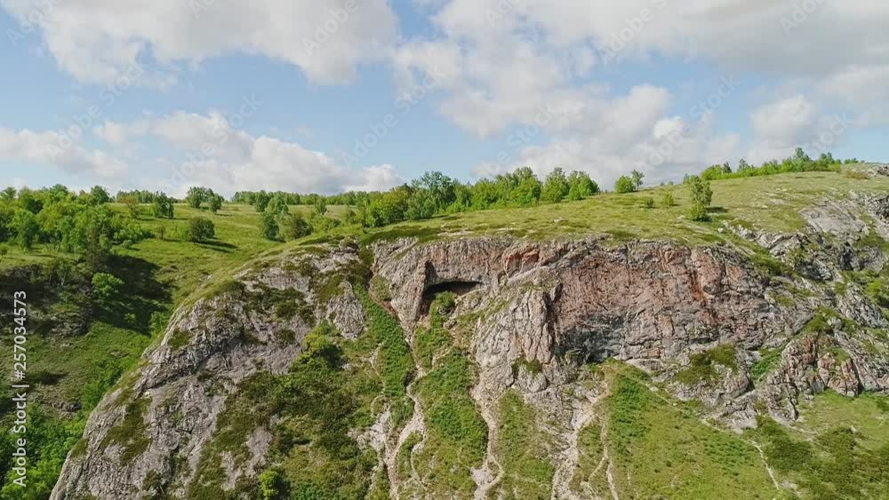 Big rocky cliff and cave in it. The camera is approaching from afar ...