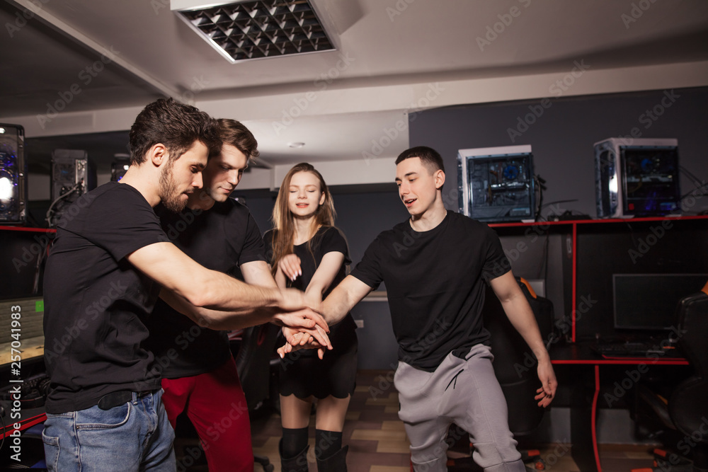 Team of male and female gamers giving high five standing in gaming club ...