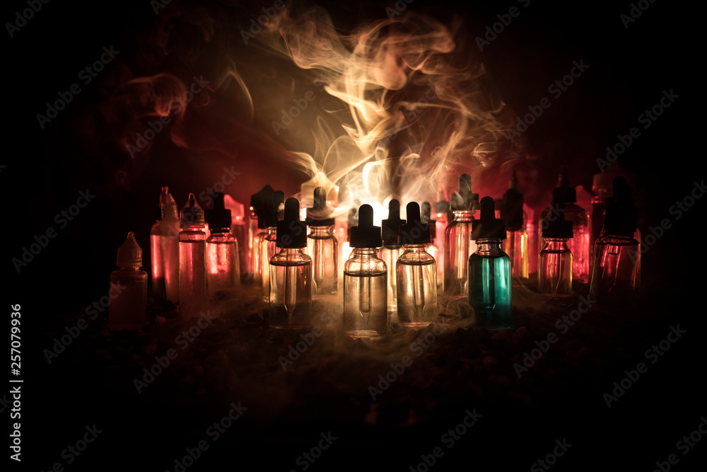 Vape concept. Smoke clouds and vape liquid bottles on dark background ...
