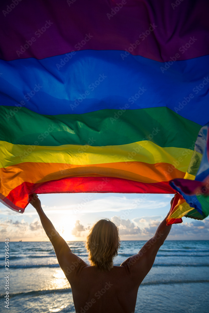 Colorful sunset silhouette of a man with blond hair holding a rainbow ...