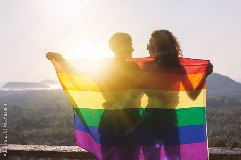 Beautiful lesbian young couple gently lovingly hugging with rainbow ...
