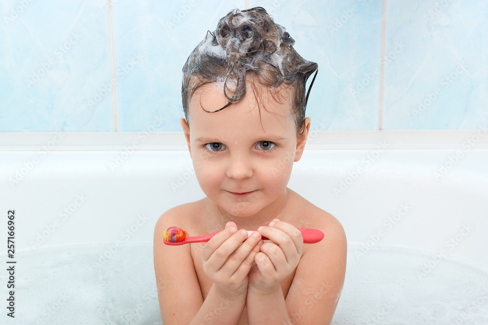 Portrait ot attractive little child looking at camera, keeps red ...