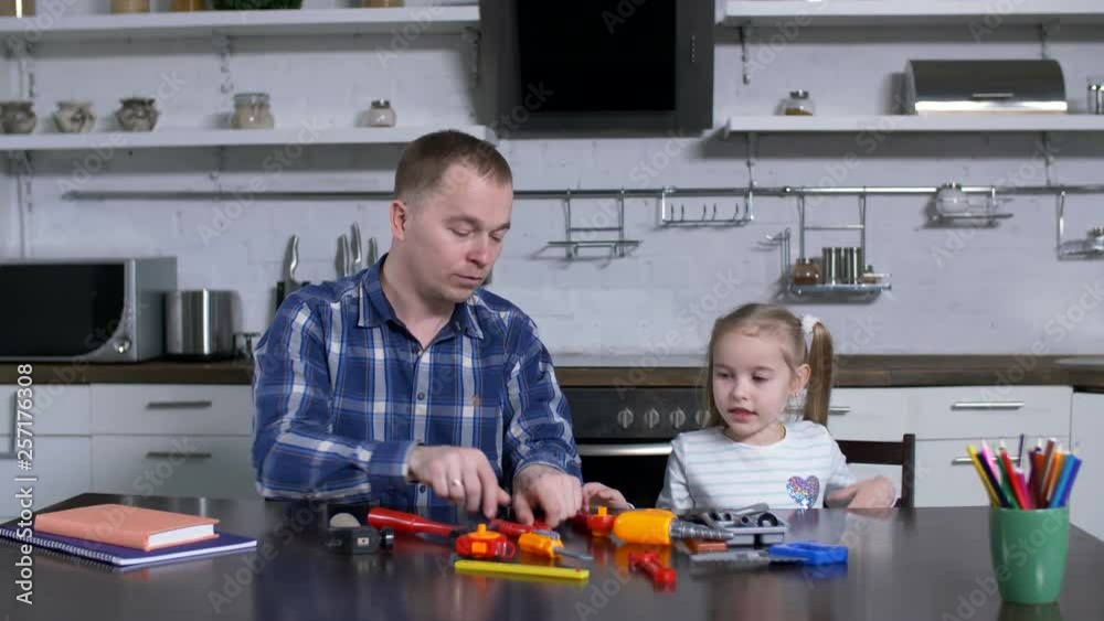 Caring father with toy set explaining to little girl use of different ...