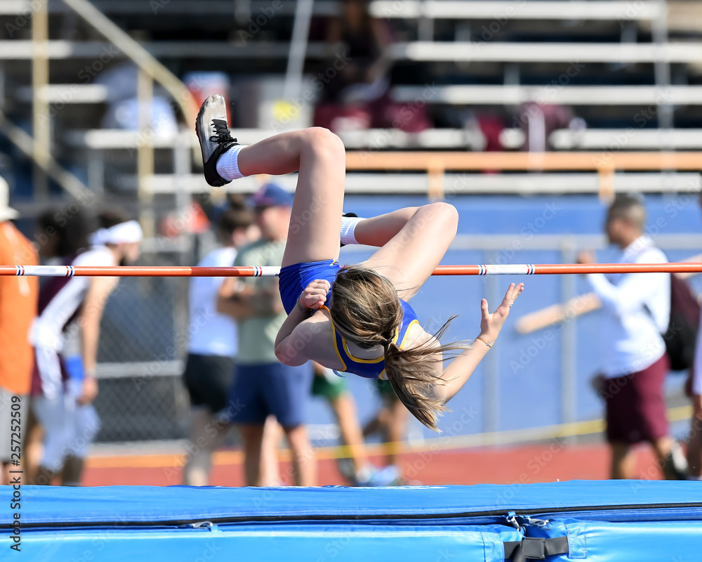 Young teenage girl competing in the high jump at a high school track ...