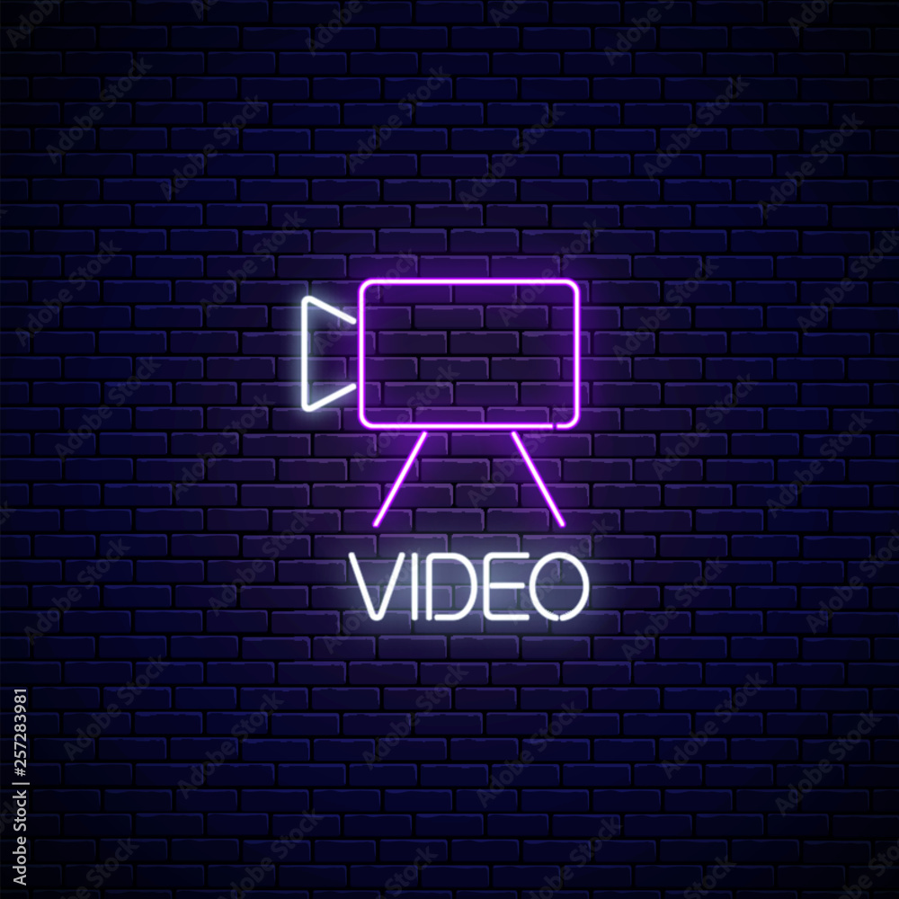 Neon sign of video camera symbol with text on dark brick wall ...